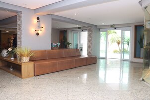 Um hall moderno com um sofá de couro, um balcão de recepção e uma porta de vidro que dá para o exterior.