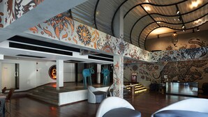 Um hall amplo com teto alto, assentos modernos e um grande mural.