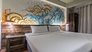 Quarto de hotel com cama grande, cabeceira de madeira e um mural colorido na parede.