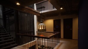 Uma escadaria com corrimão de madeira, um candeeiro pendente e vista para o exterior.