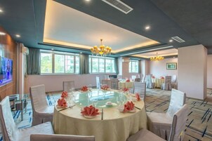 Sala de conferências com mesa redonda, cadeiras e um candelabro.