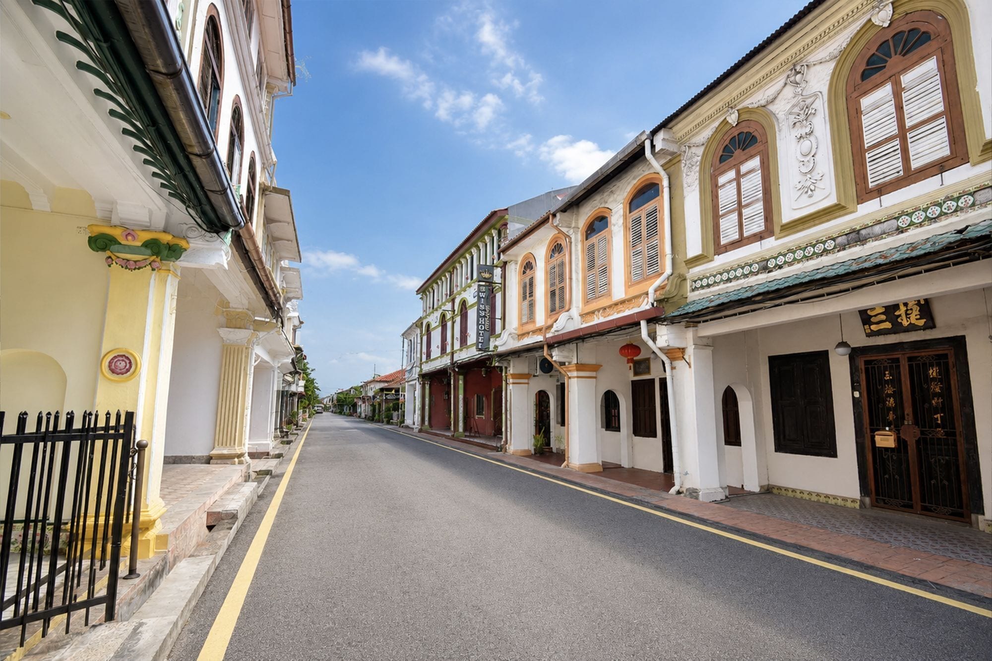 Rua flanqueada por edifícios em estilo colonial, incluindo um hotel com uma placa.