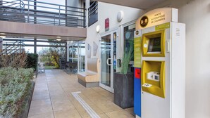 Um edifício moderno com galeria coberta, máquina de vendas automática e escadaria.