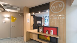 Uma receção com o logótipo B&B Hotels e uma placa de boas-vindas em francês.
