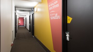 Um corredor com parede amarela e vermelha, uma porta preta com um número e um extintor de incêndio.