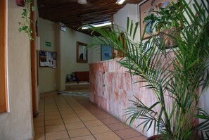 Um corredor com piso de azulejos, teto de madeira e um pilar de mármore.