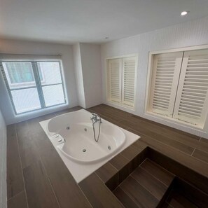 Uma casa de banho moderna com uma banheira independente, chuveiro e janela com persianas.