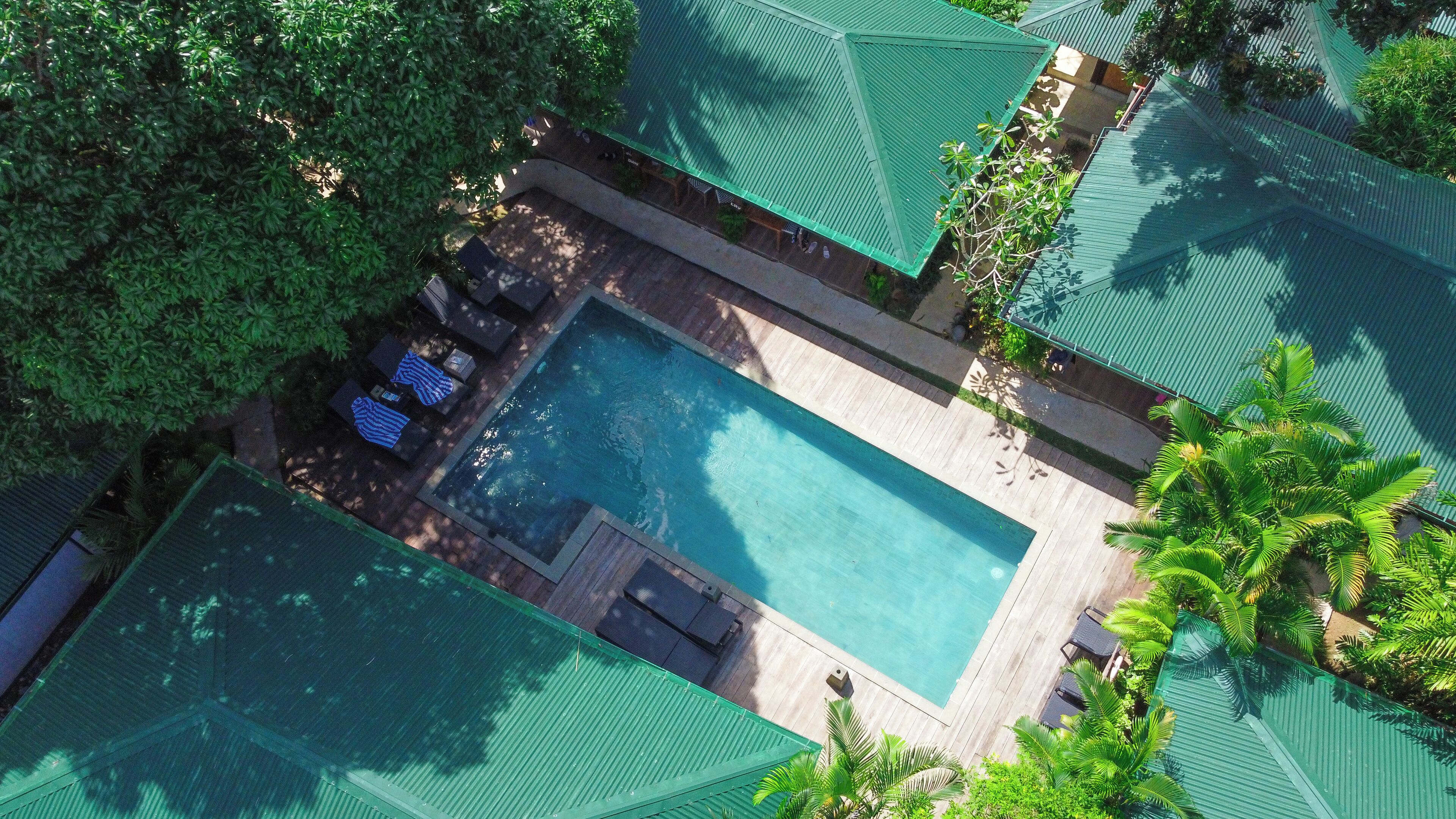 Vista aérea de um resort com piscina, cadeiras de descanso e um espaço coberto com varanda.