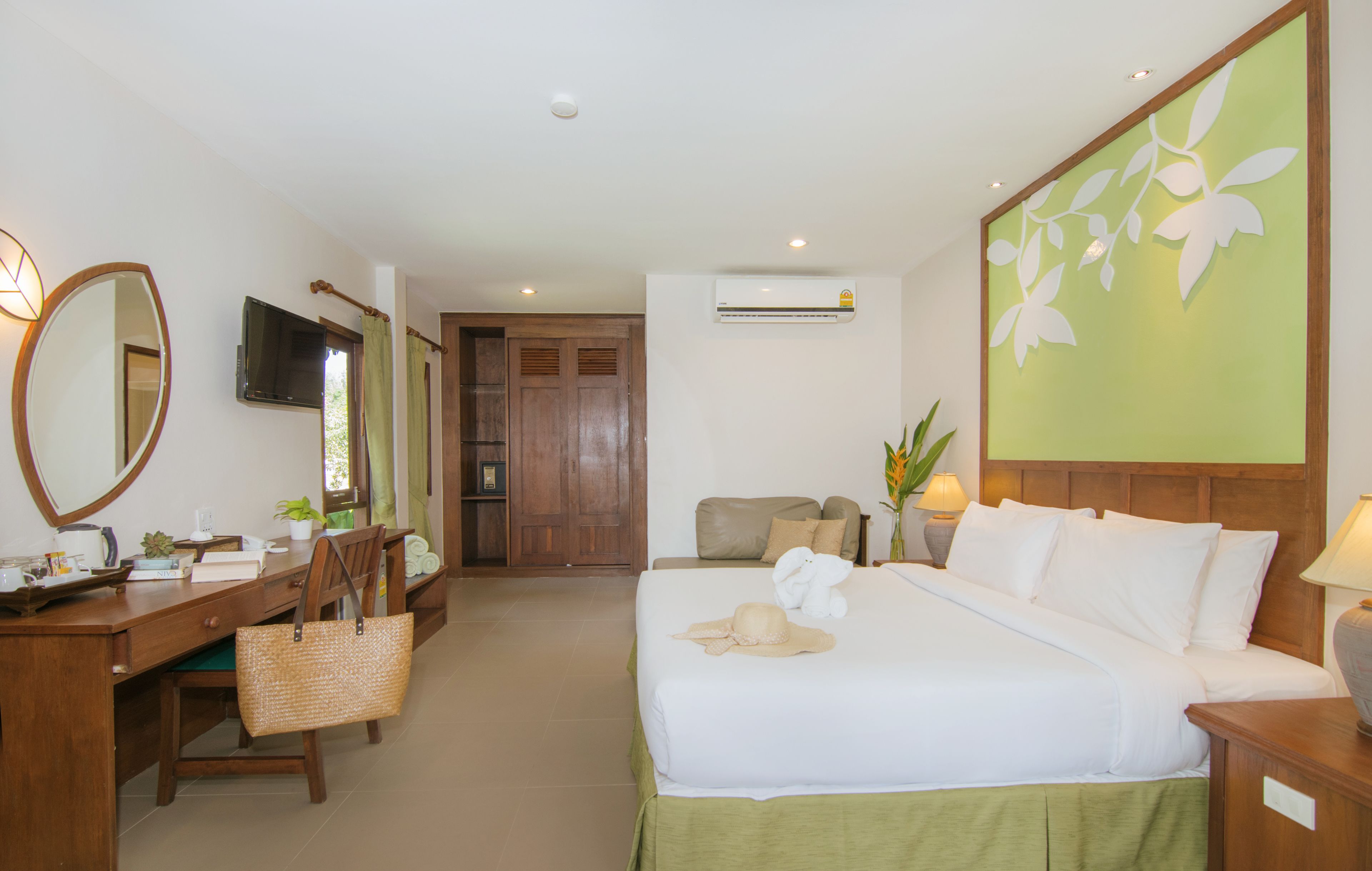Quarto de hotel com cama, escrivaninha, cadeira, televisão e uma janela grande.