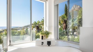 Quarto moderno com amplas janelas, uma pequena planta e uma tomada.