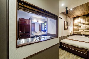 Quarto de hotel pequeno com um espelho grande, uma pia moderna, uma cama e uma cabeceira de madeira.
