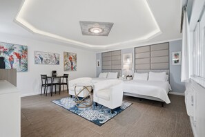 Quarto de hotel moderno com uma cama grande, uma escrivaninha com cadeira e obras de arte nas paredes.