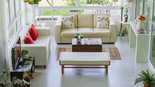 Uma sala de estar espaçosa com uma grande janela, um candelabro, um sofá e uma mesa de centro.