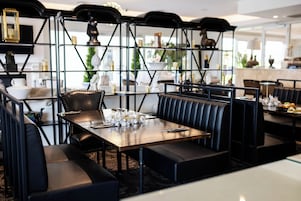 Restaurante com assentos de couro preto e mesa de madeira posta para refeição.