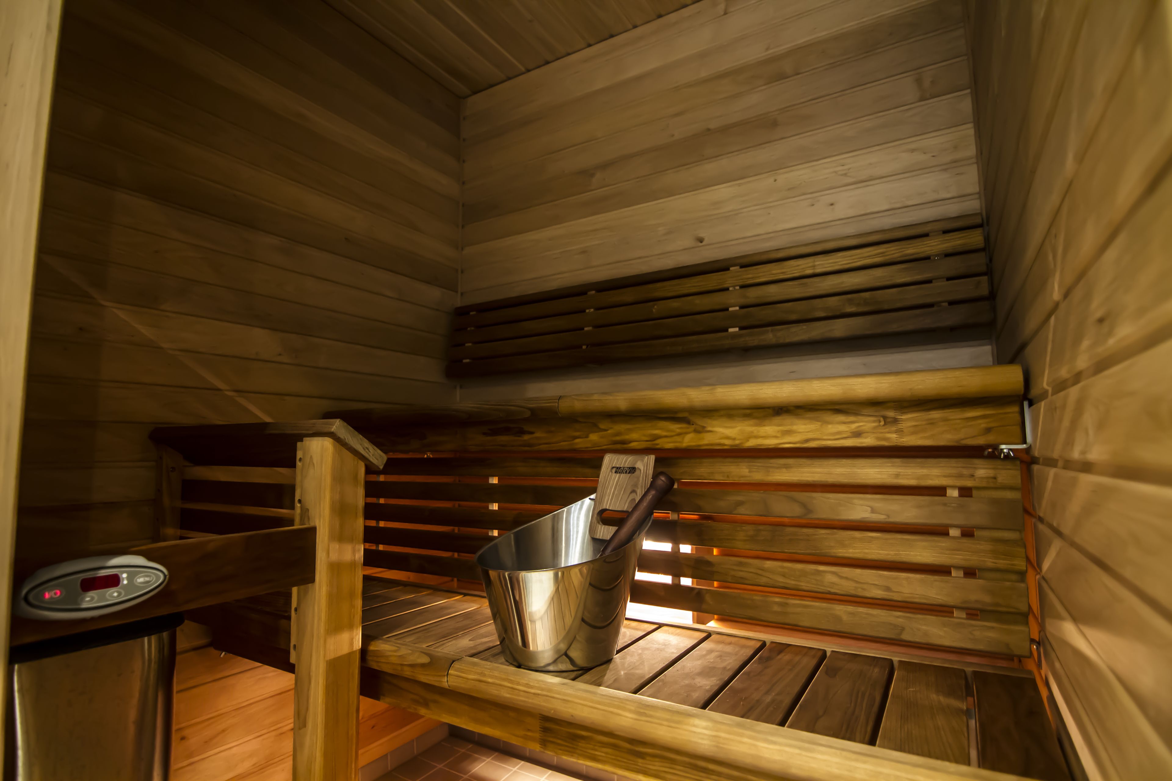 Uma sauna com bancos de madeira e um balde de metal.