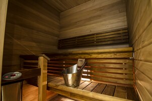Uma sauna com bancos de madeira e um balde de metal.