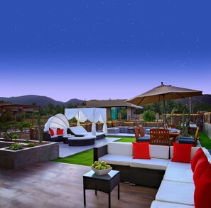 Um pátio externo com área de estar, uma mesa com uma tigela de maçãs e vista do céu noturno.
