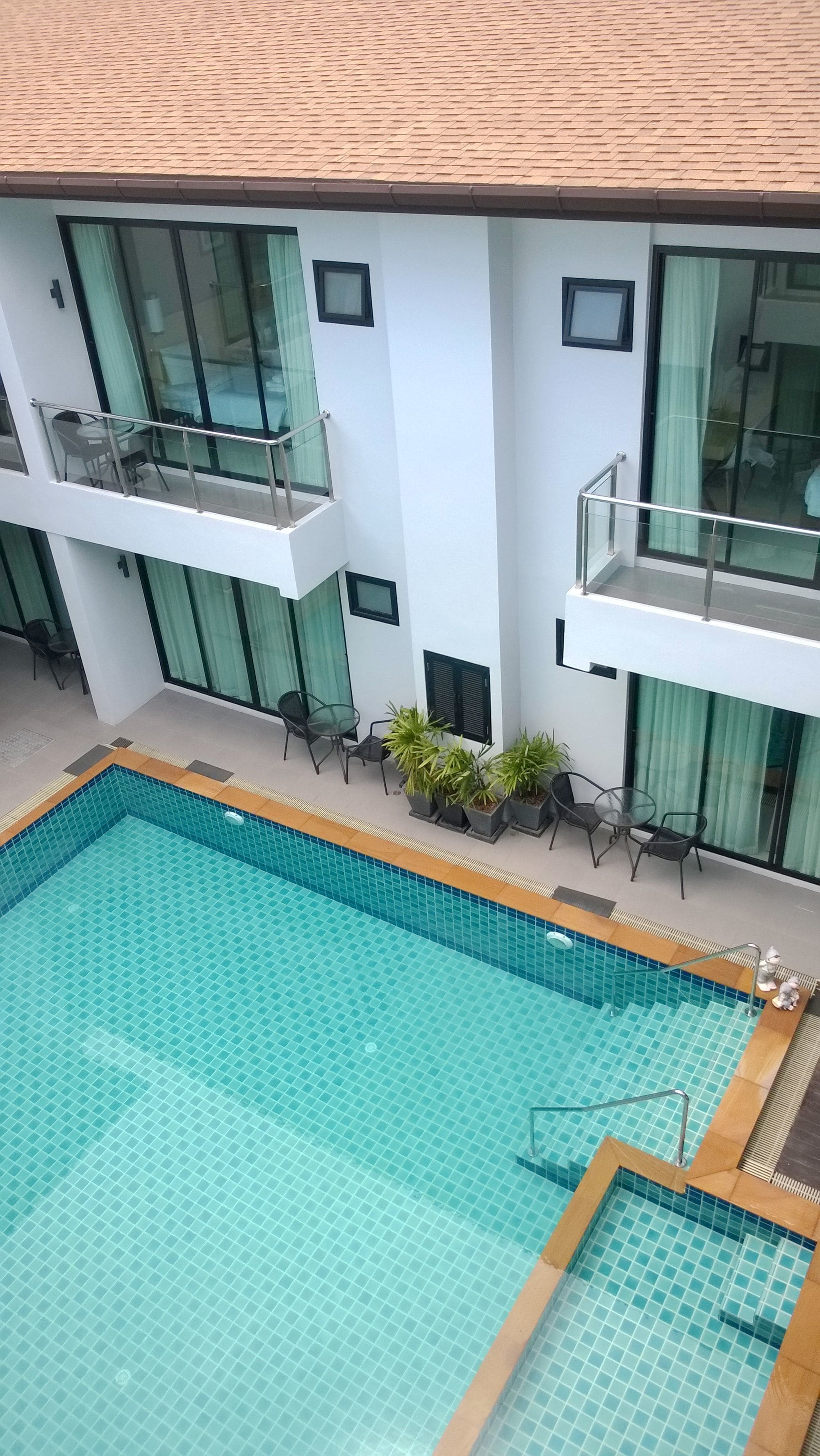 Um hotel moderno com uma piscina grande ao ar livre, várias varandas e áreas de estar externas.