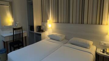 Quarto de hotel com cama, mesas de cabeceira, escrivaninha e uma cadeira.