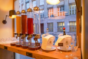 Uma área de bar com diversos dispensadores de bebidas, copos e uma garrafa de água com gás.