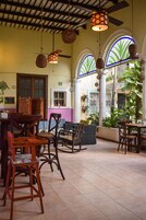 Um espaço amplo e interno com móveis de madeira, luminárias pendentes e grandes janelas com molduras azuis.