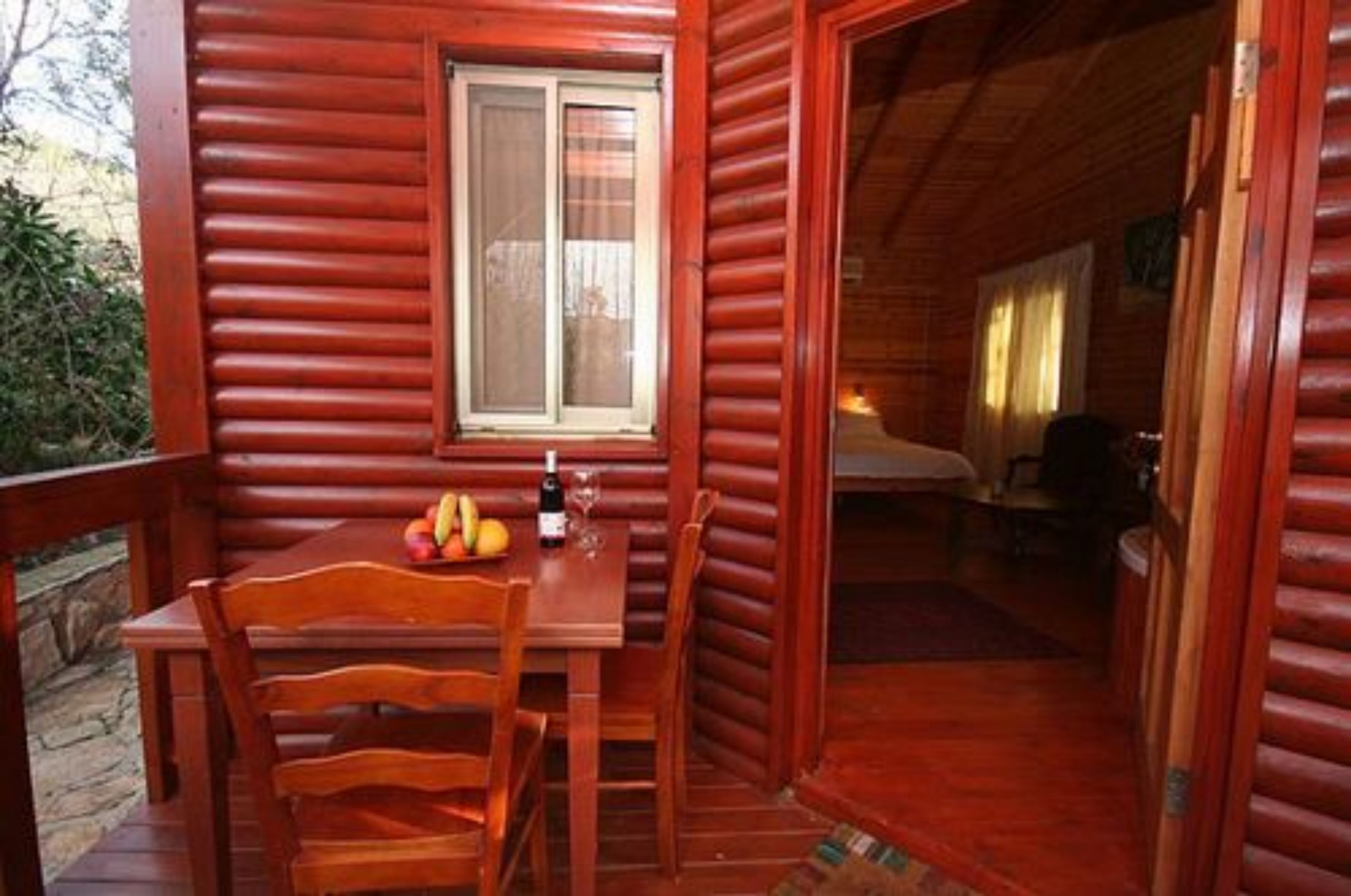 Uma cabana de madeira com área de refeições, uma janela e um quarto visível por uma porta aberta.