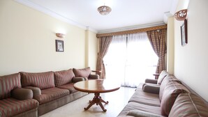 Sala de estar com sofá, mesa de centro redonda e janela com cortinas.
