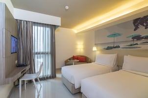 Quarto de hotel com duas camas, uma escrivaninha com cadeira, televisão e um quadro de guarda-chuvas.