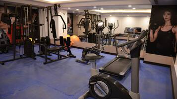 Academia com equipamentos de ginástica, esteira e parede espelhada.