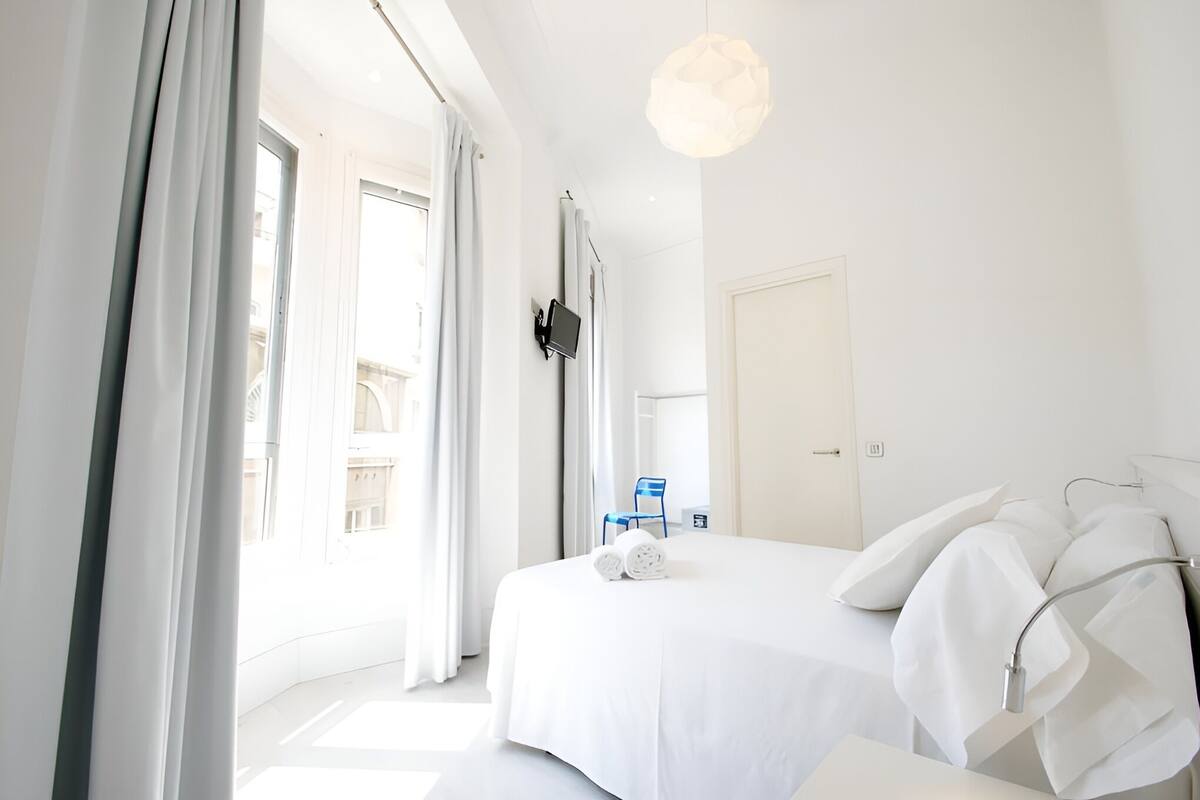 Quarto de hotel moderno com uma cama grande, televisão de tela plana na parede e vista para a varanda.