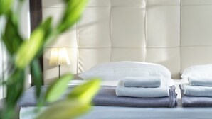Cama bem arrumada com toalhas dobradas e luminária de cabeceira.