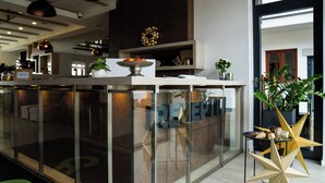 Uma área de recepção moderna com divisória de vidro, balcão de atendimento e uma mesa decorativa em formato de estrela.