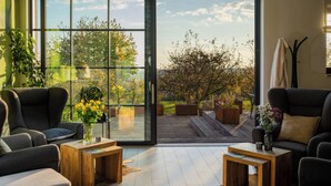 Uma sala de estar moderna com uma grande porta de vidro deslizante que dá para um deck externo, mobiliada com sofás e uma mesa de centro.