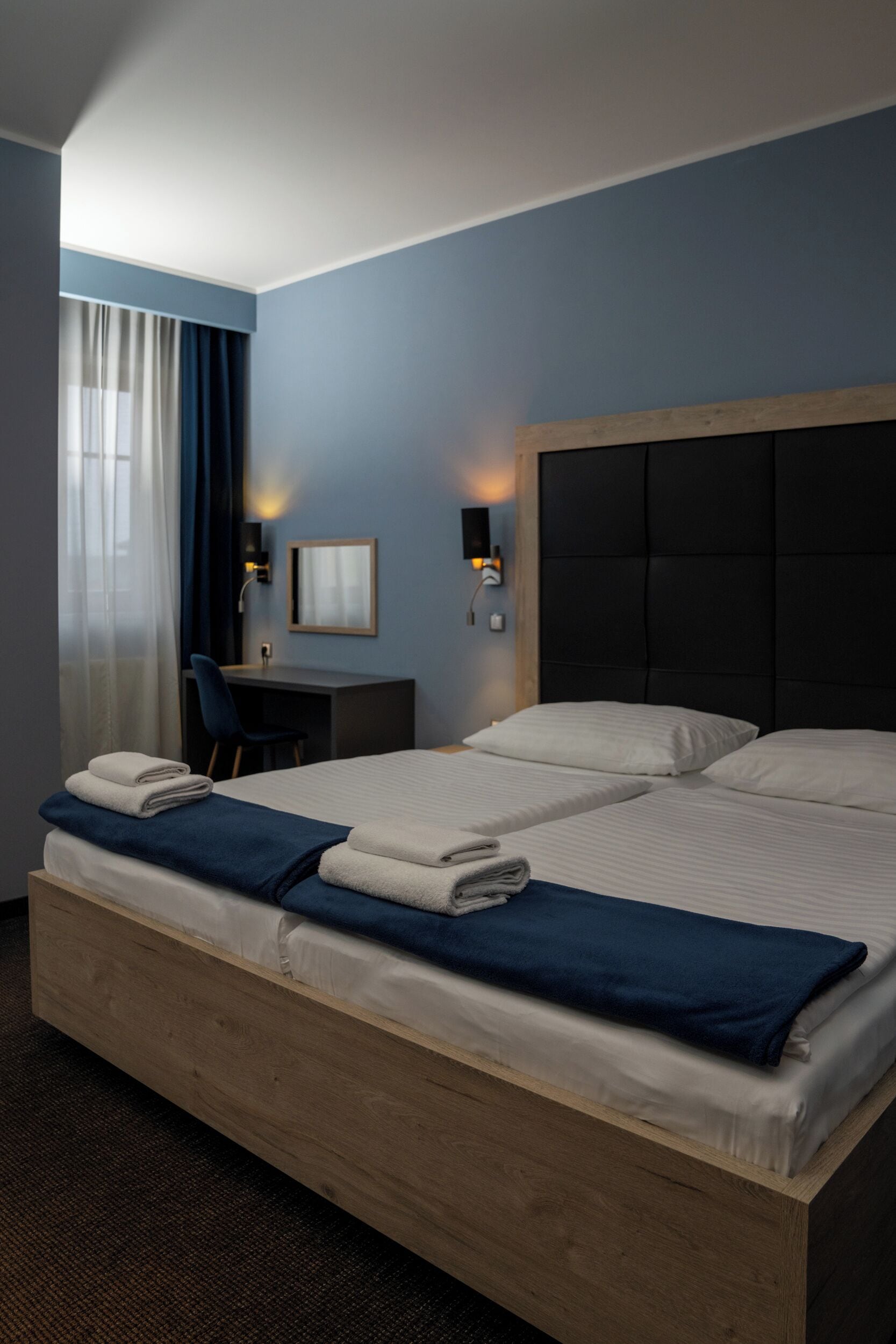 Quarto de hotel com uma cama grande, uma escrivaninha e uma cadeira.