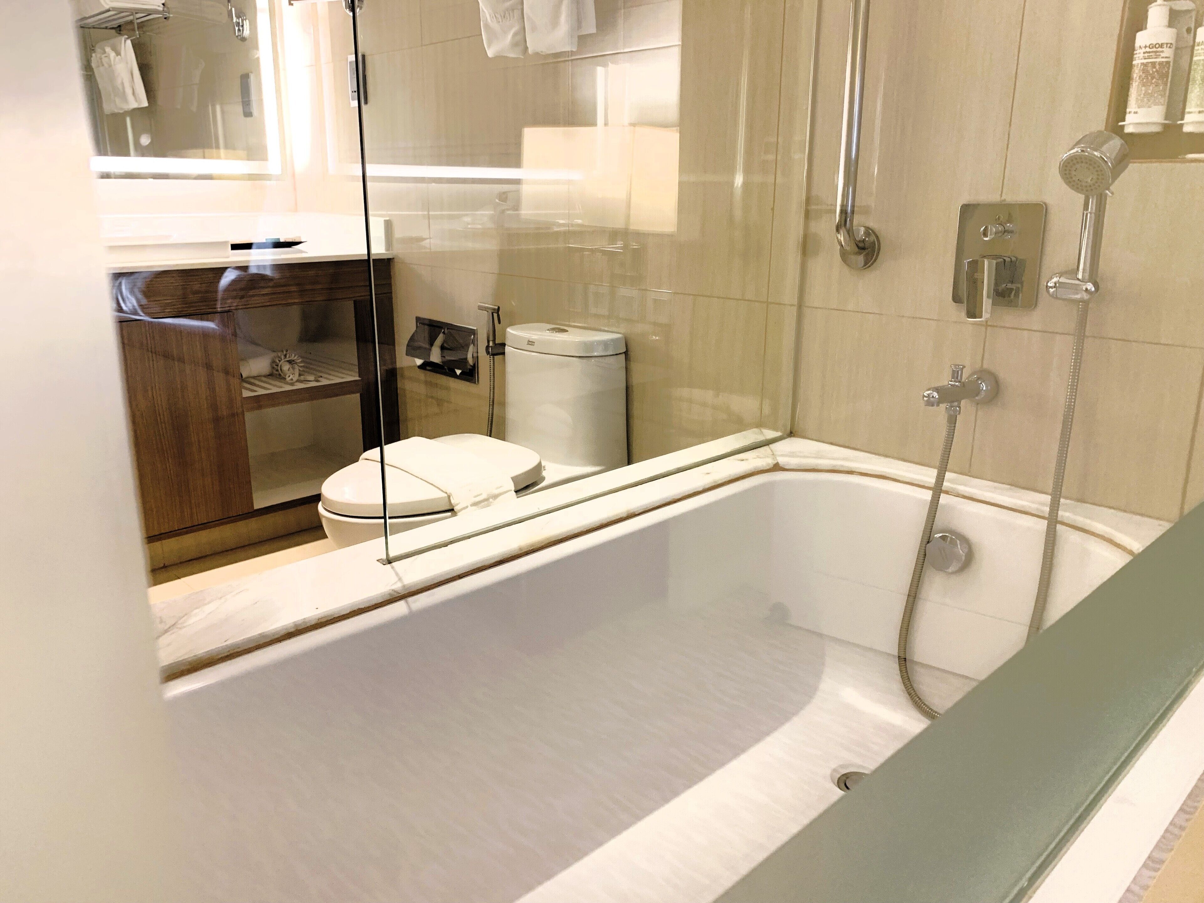Um banheiro moderno com chuveiro em gabinete de vidro, vaso sanitário branco e toucador de madeira.
