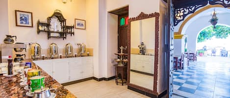 Cozinha de hotel com bancadas de mármore, um espelho grande e vista para o pátio externo.