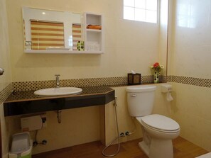 Casa de banho com lavatório, sanita e espelho.