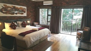 Um quarto com uma cama grande, parede de tijolos, janela com cortinas e uma varanda.