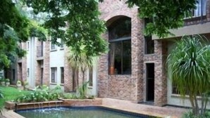 Pátio com piscina, rodeado por edifícios de tijolo e vegetação exuberante.