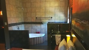 Quarto de hotel moderno com uma cama grande, chuveiro integrado e banheiro pequeno.