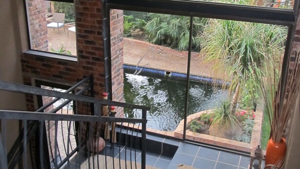 Uma escadaria leva a uma varanda com vista para um jardim e um lago.