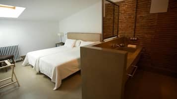 Quarto de hotel com cama, escrivaninha, cadeira, espelho grande e banheira.