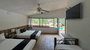Quarto de hotel com duas camas, um ventilador de teto, uma televisão e uma janela com vista para o exterior.