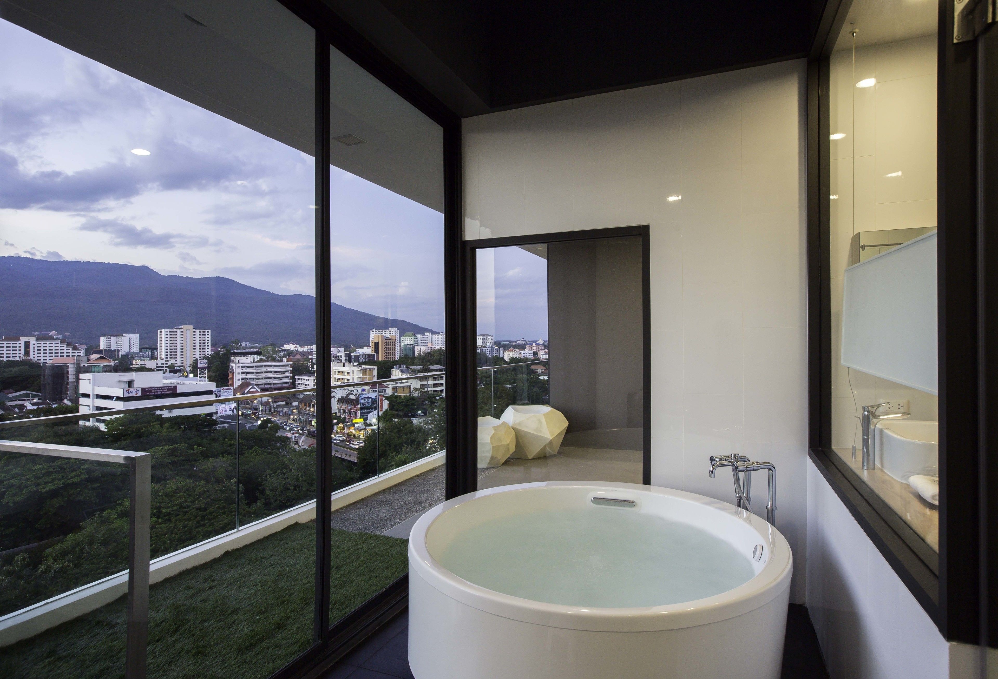 Um banheiro moderno com uma banheira grande e vista para a cidade.