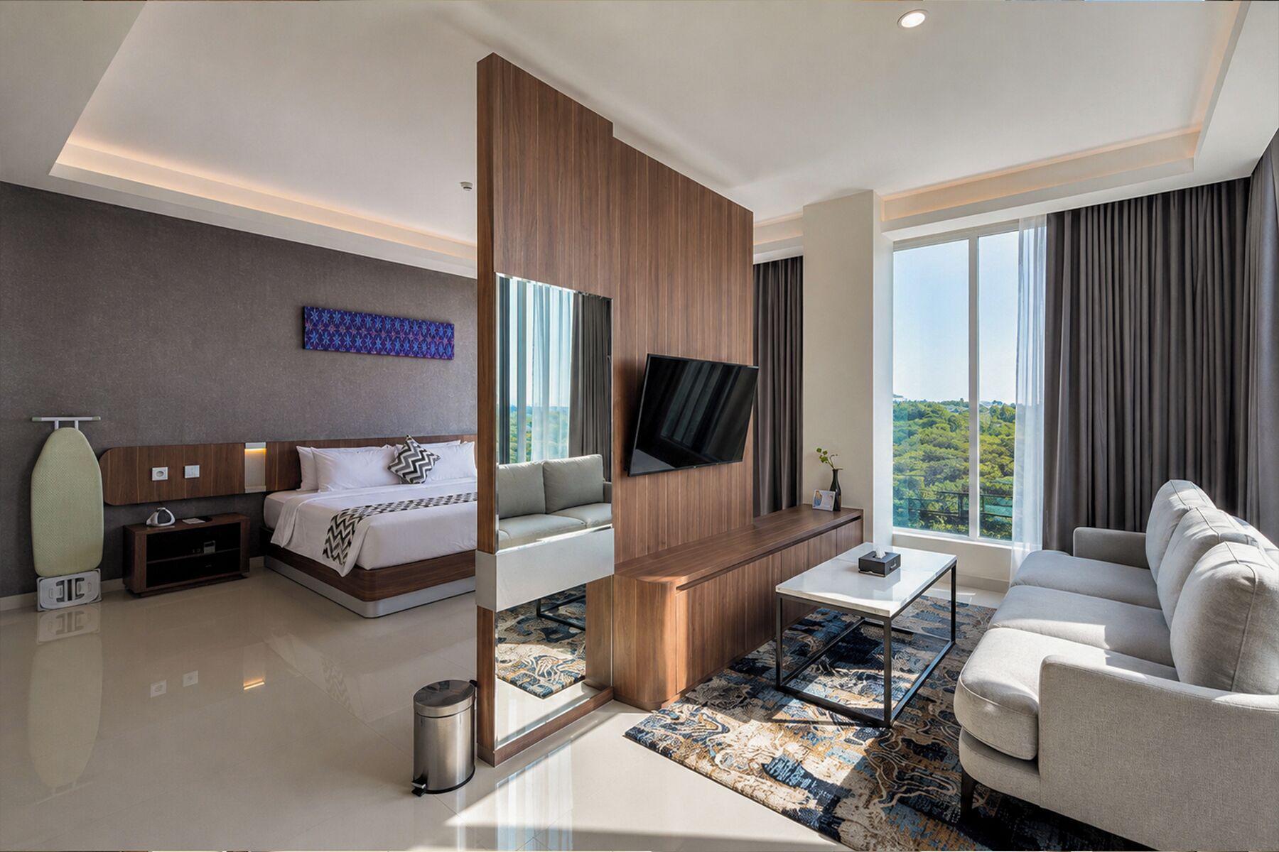 Quarto de hotel moderno com cama, sofá, TV e vista para o exterior.