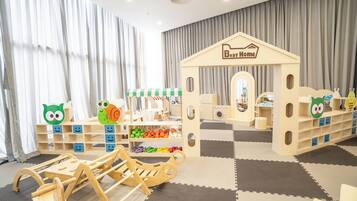 Quarto para bebês com área de recreação, trocador e placa 'Baby Home'.