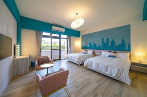 Quarto de hotel com duas camas, área de estar com uma mesa e um mural com vista para a cidade na parede.