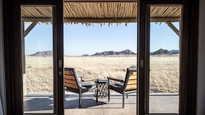 Quarto com vista para uma paisagem desértica através de portas deslizantes abertas.