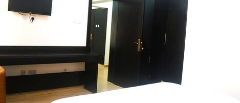 Um quarto com cama, escrivaninha e guarda-roupa.