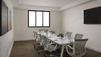 Uma sala de conferências com uma mesa comprida, cadeiras e uma janela grande.
